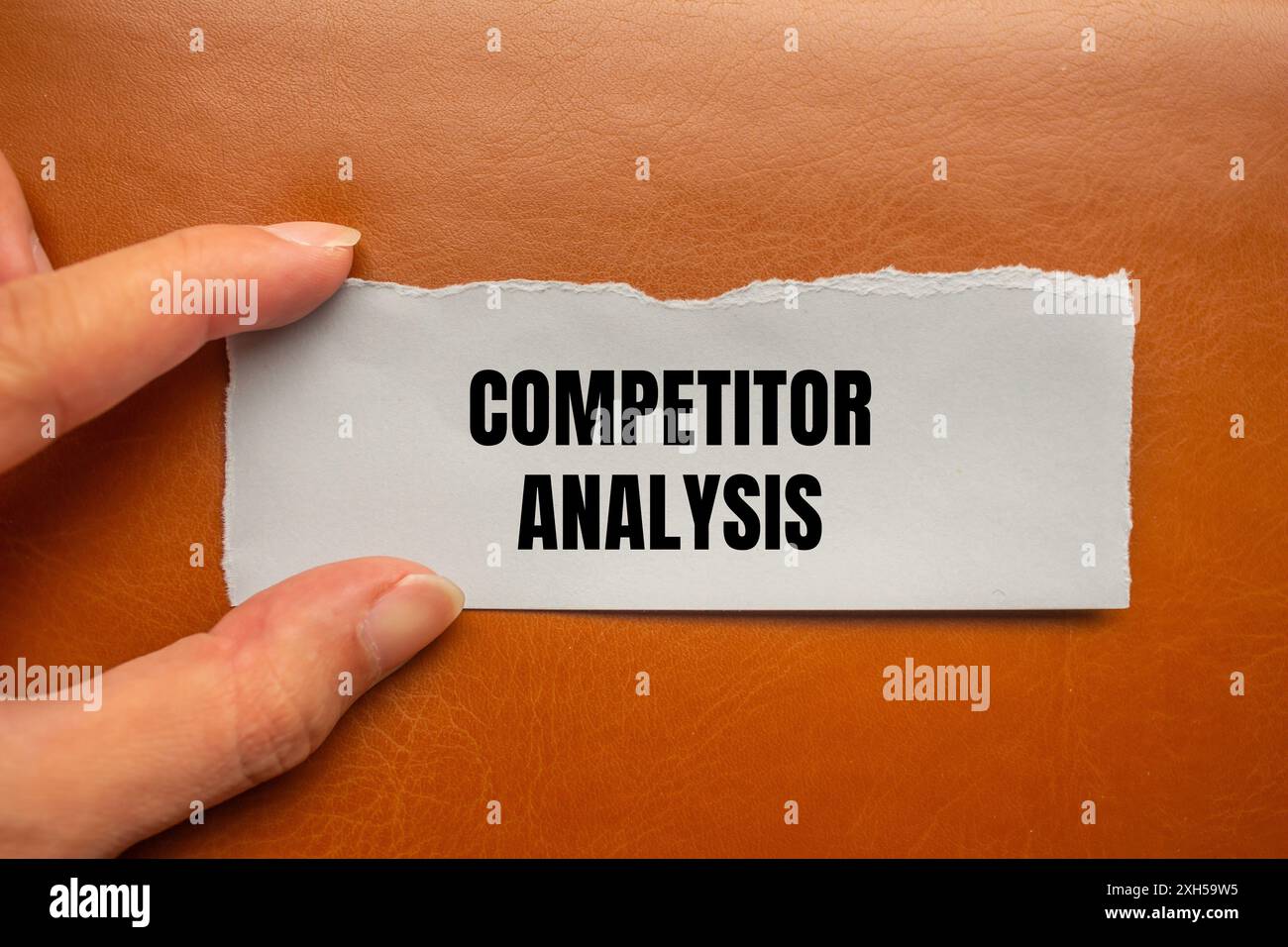 Competitor analysis message written on ripped paper piece with brown ...