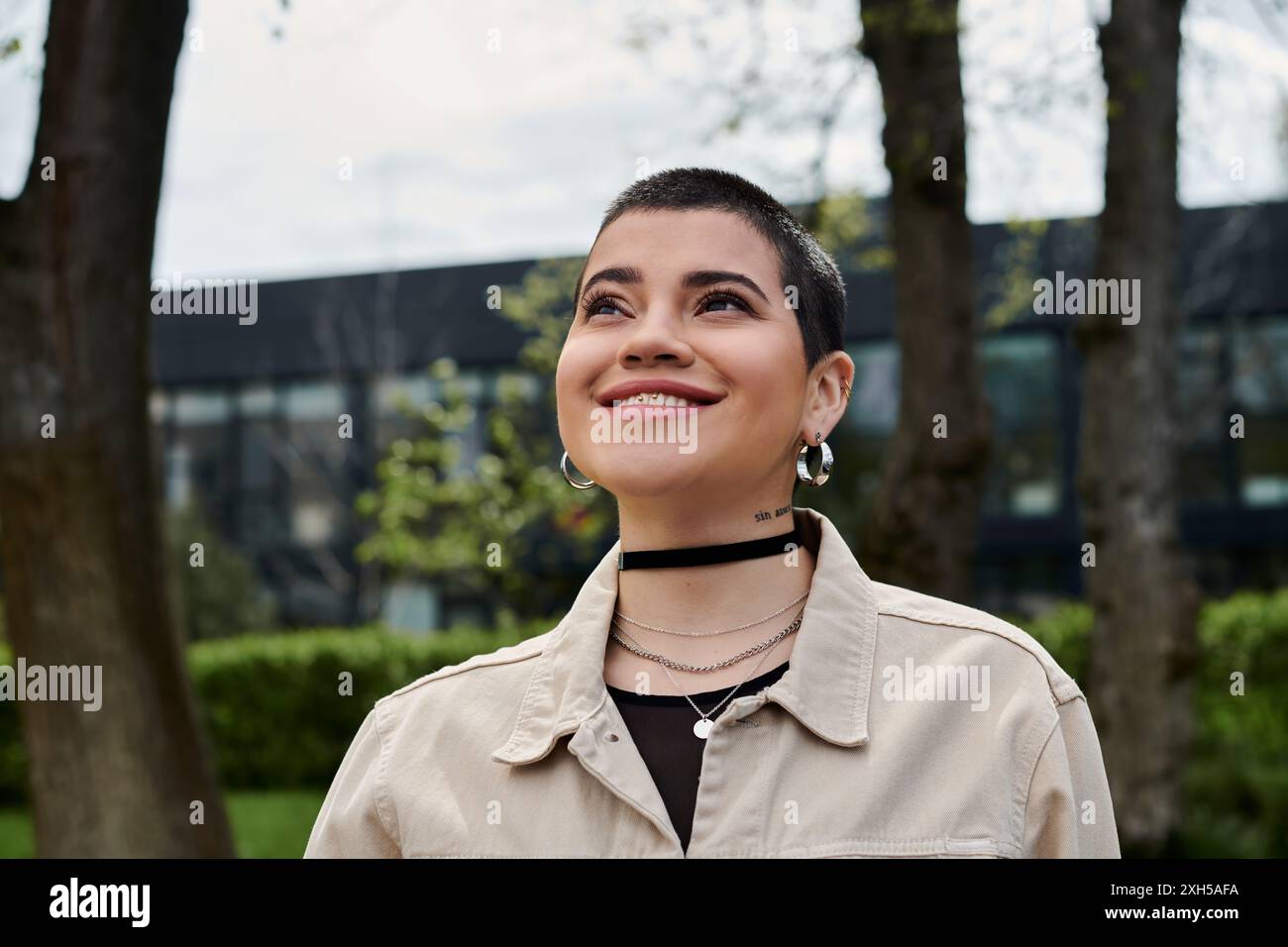 A serene woman standing gracefully in front of a backdrop of lush trees ...