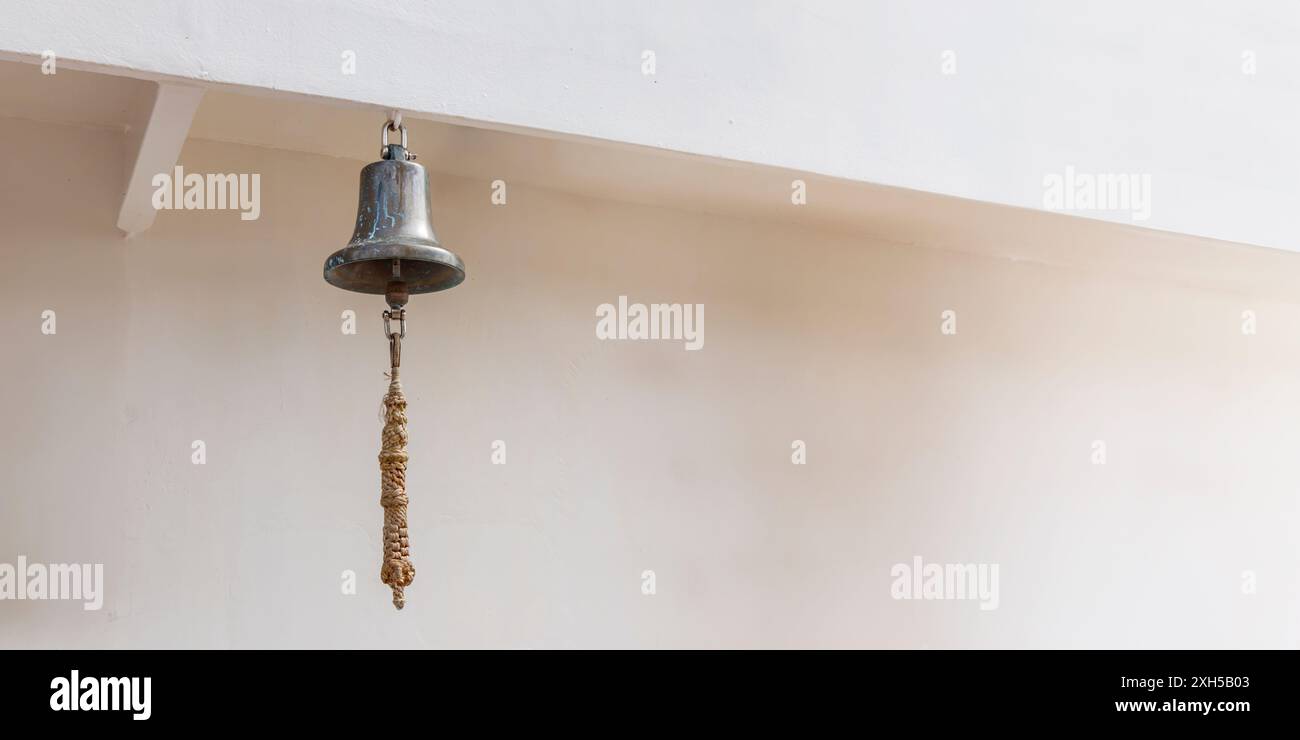 Ship's bell on a white wall against a blue sky on a sailing ship Stock ...