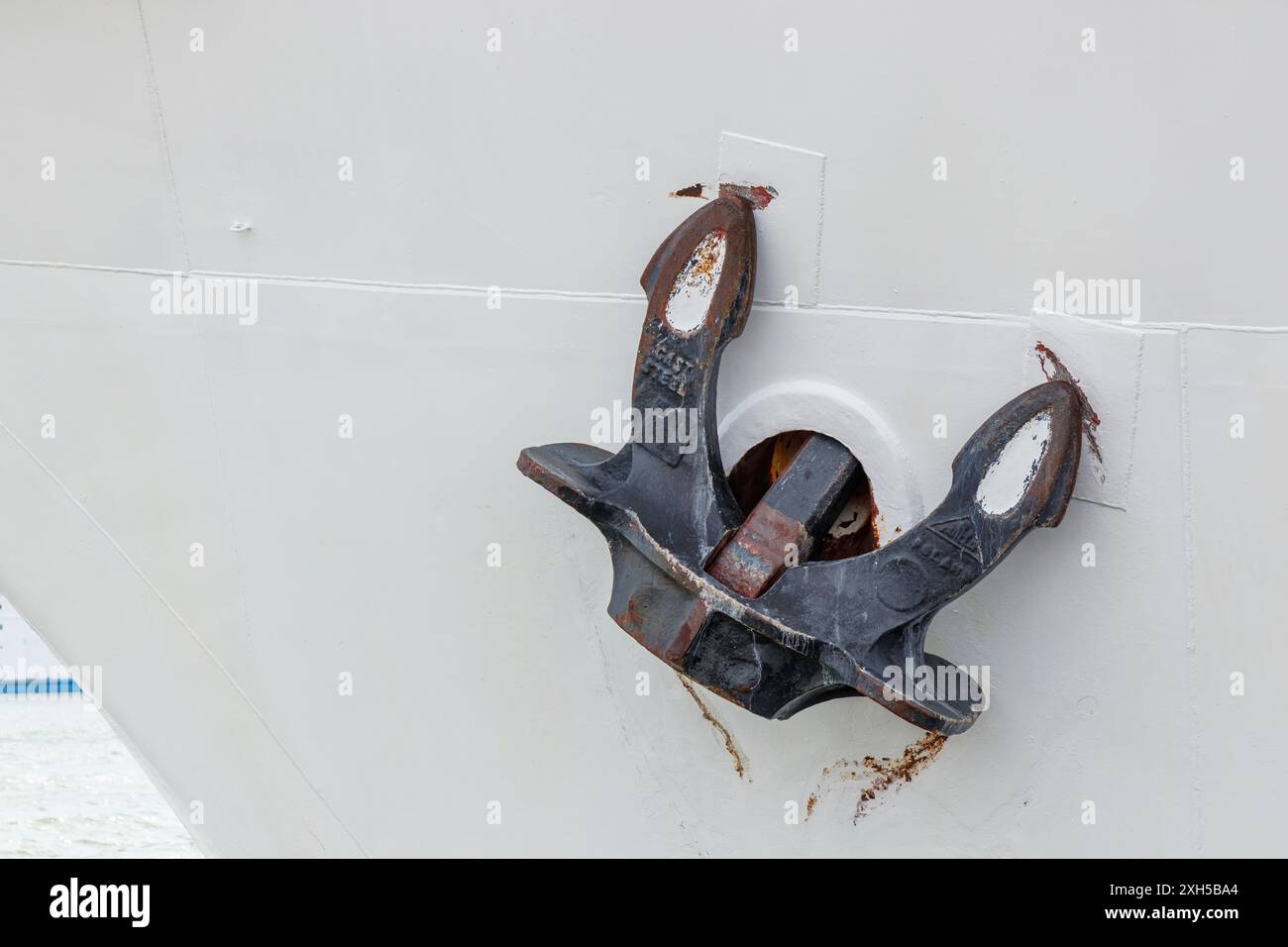 View of a rusted ship's anchor on the anchor hole of a white ship on ...