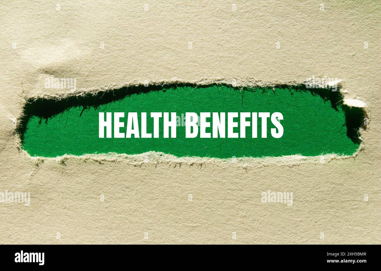 Health benefits message written on ripped torn paper with green background. Conceptual health ...