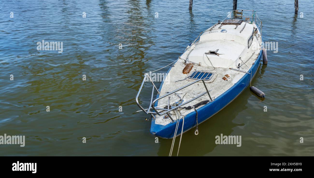 Close up of an old, dirty, crushed neglected abandoned sailing boat in ...