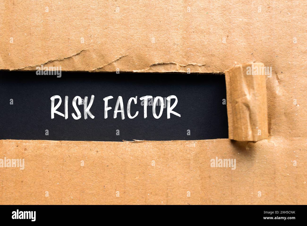 Risk factor message written on ripped torn cardboard paper with black background. Conceptual ...