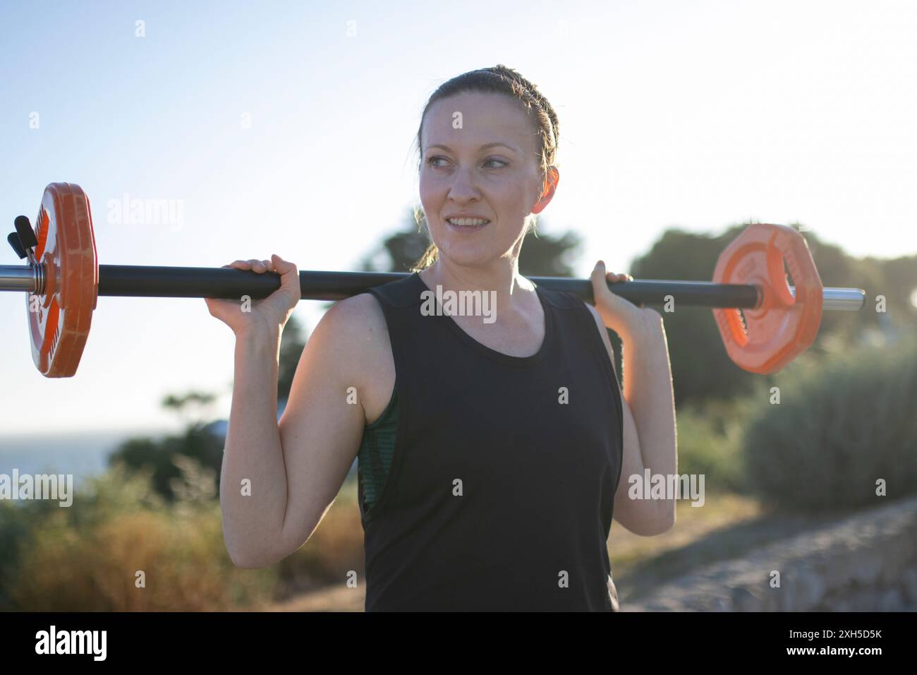 A woman is lifting a weight bar with a smile on her face Stock Photo ...