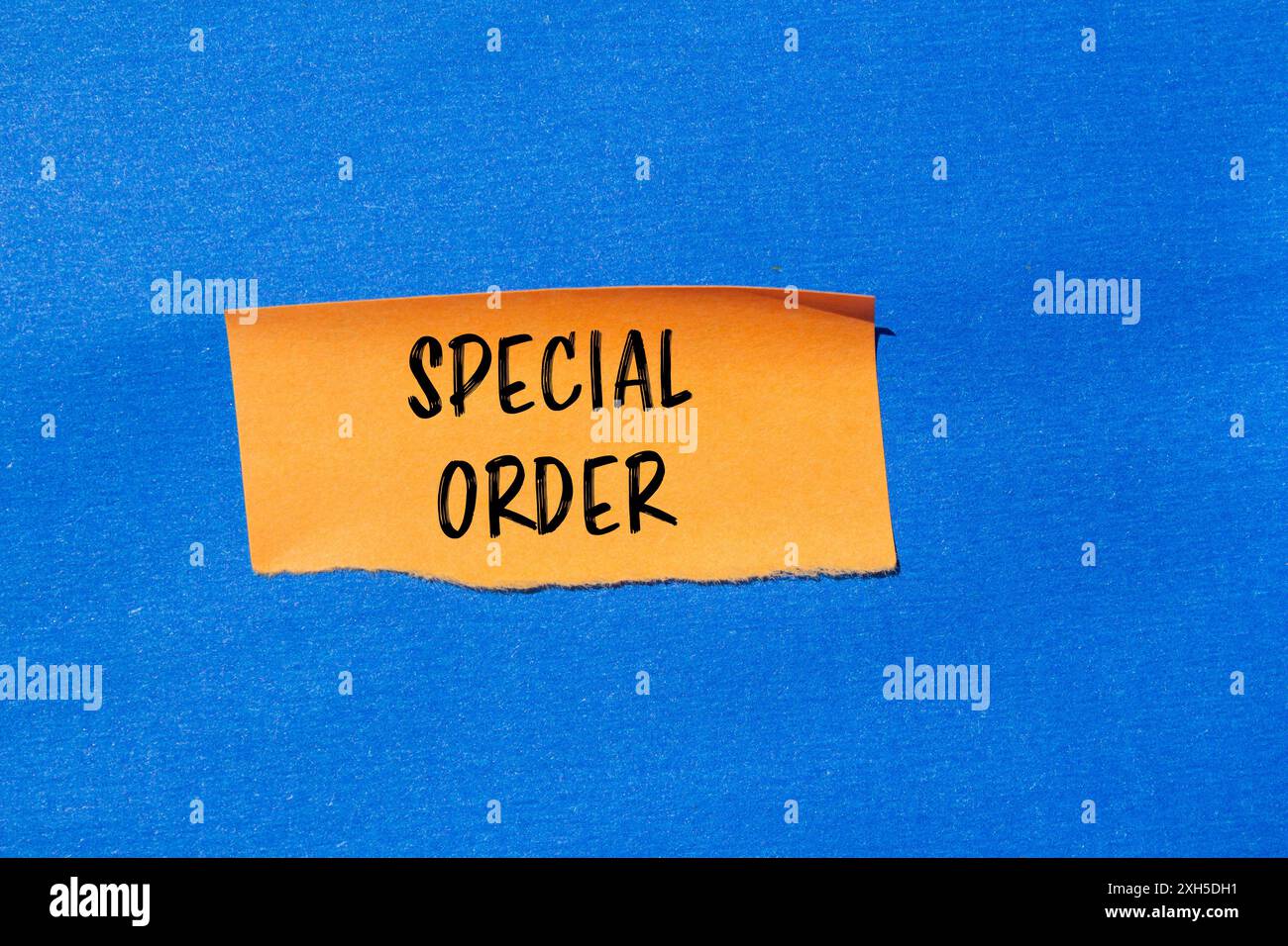 Special order message written on ripped torn orange paper piece with blue background. Conceptual ...