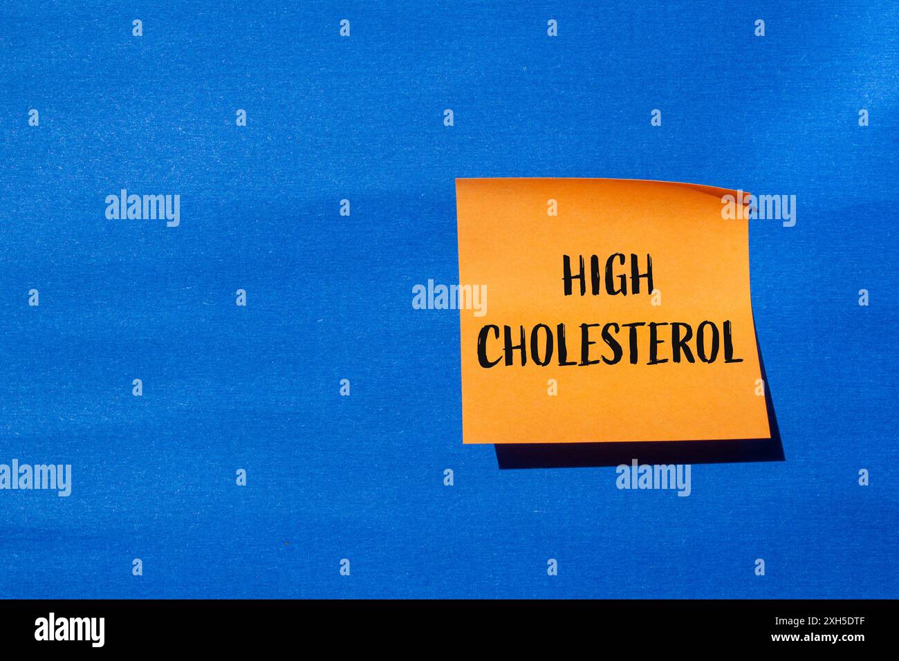 High cholesterol message written on orange paper with blue background ...