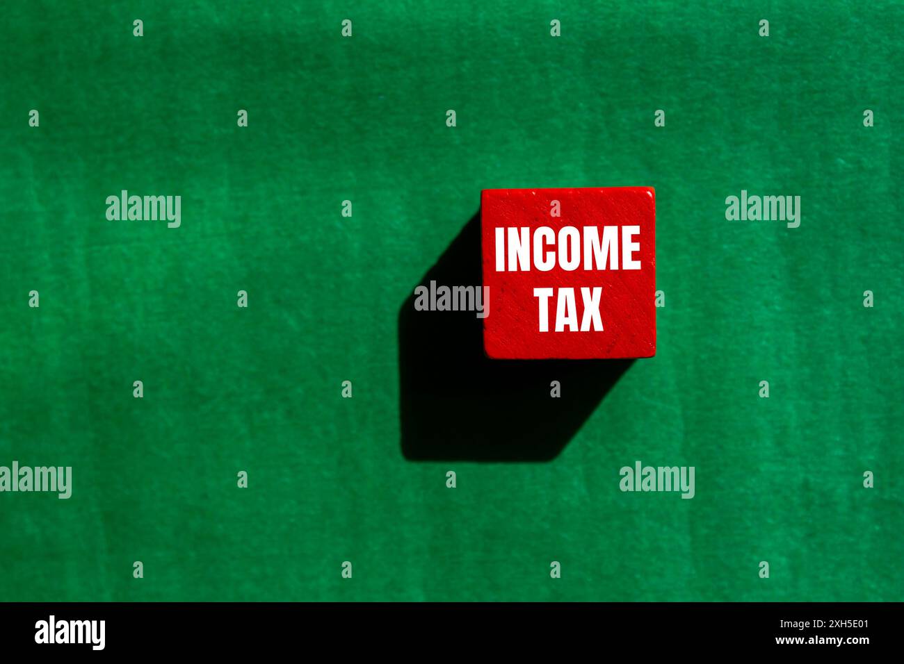 Income tax message written on red wooden cube with green background ...