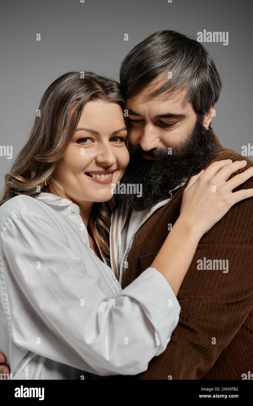 A loving couple poses together, the woman smiling warmly as she rests ...