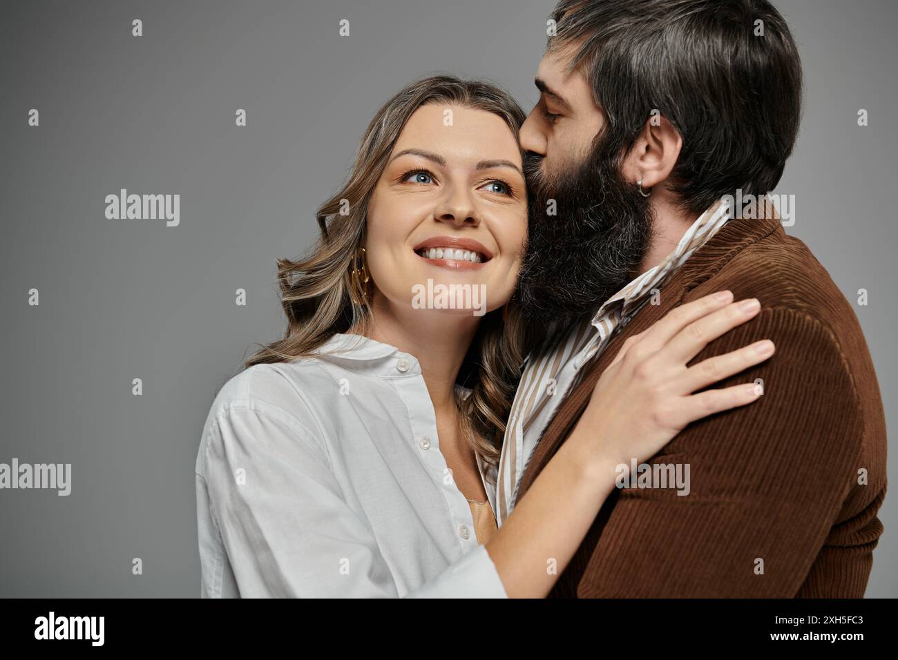 A loving couple poses together, the man gently kissing the womans ...