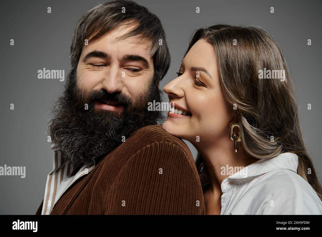 A loving couple in sophisticated attire pose together, the woman ...
