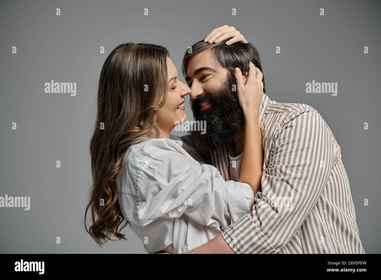A loving couple in sophisticated attire embrace in a studio setting ...