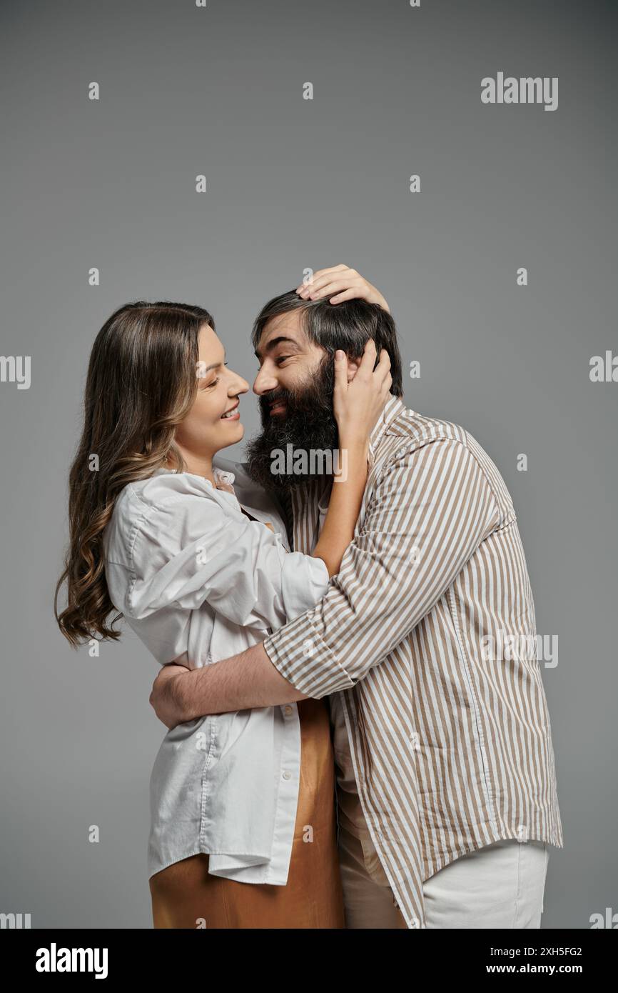 A man and woman in sophisticated attire pose close together, looking ...