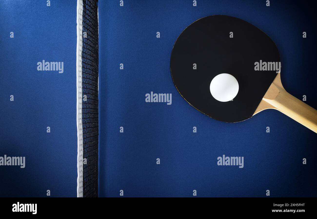 Table tennis paddle and white ball on blue game table with net. Top ...
