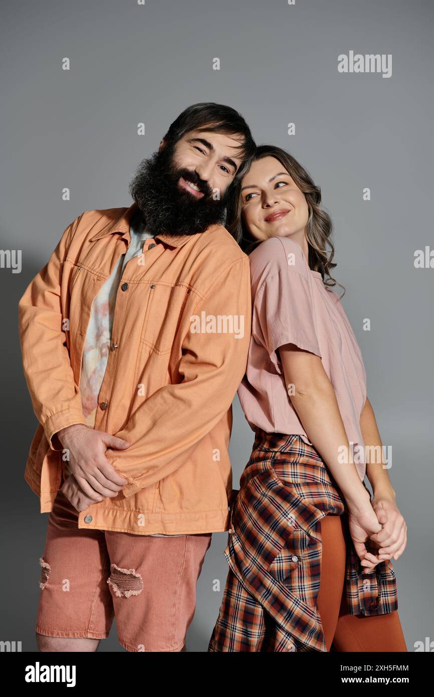 A man and woman in stylish attire stand closely together, showcasing a ...