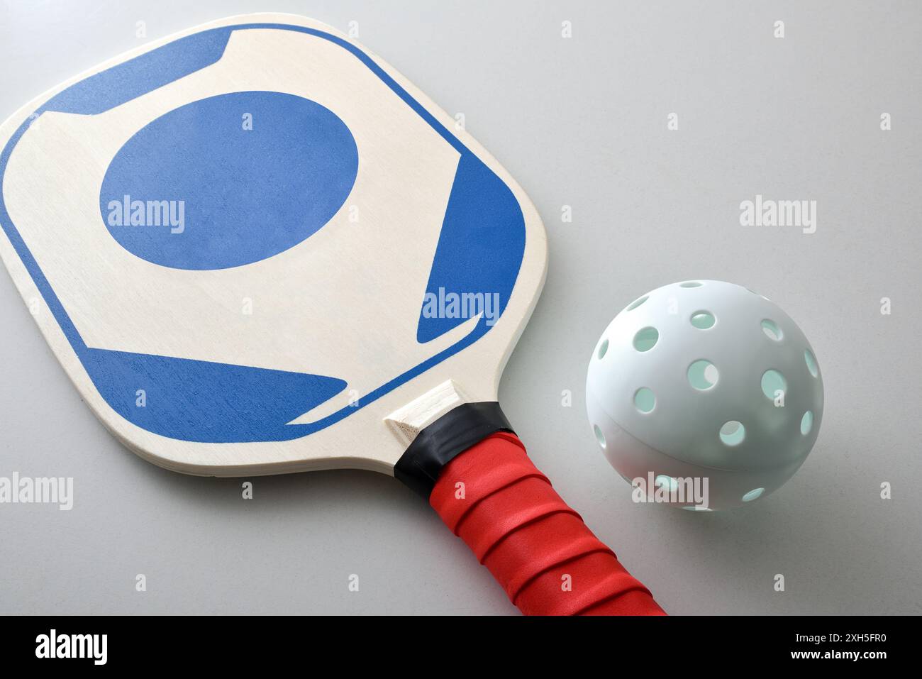 Detail of pickleball racket and a white ball isolated on white table ...