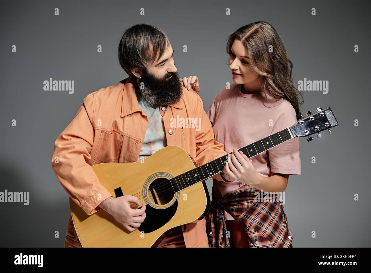 A loving couple poses together in a studio setting, the man playing a ...