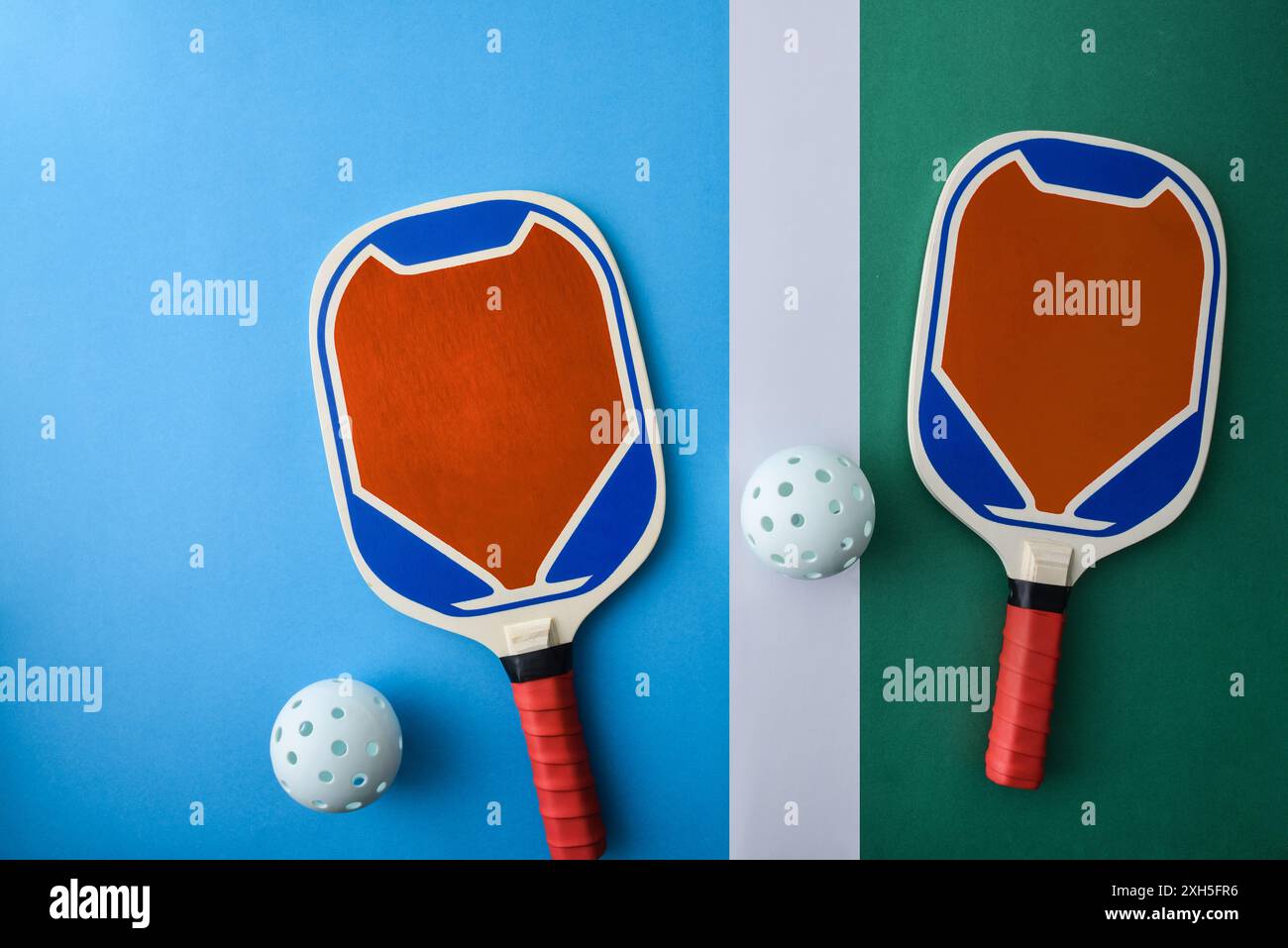 Blue and orange wooden pickleball paddles and a white ball on playing ...