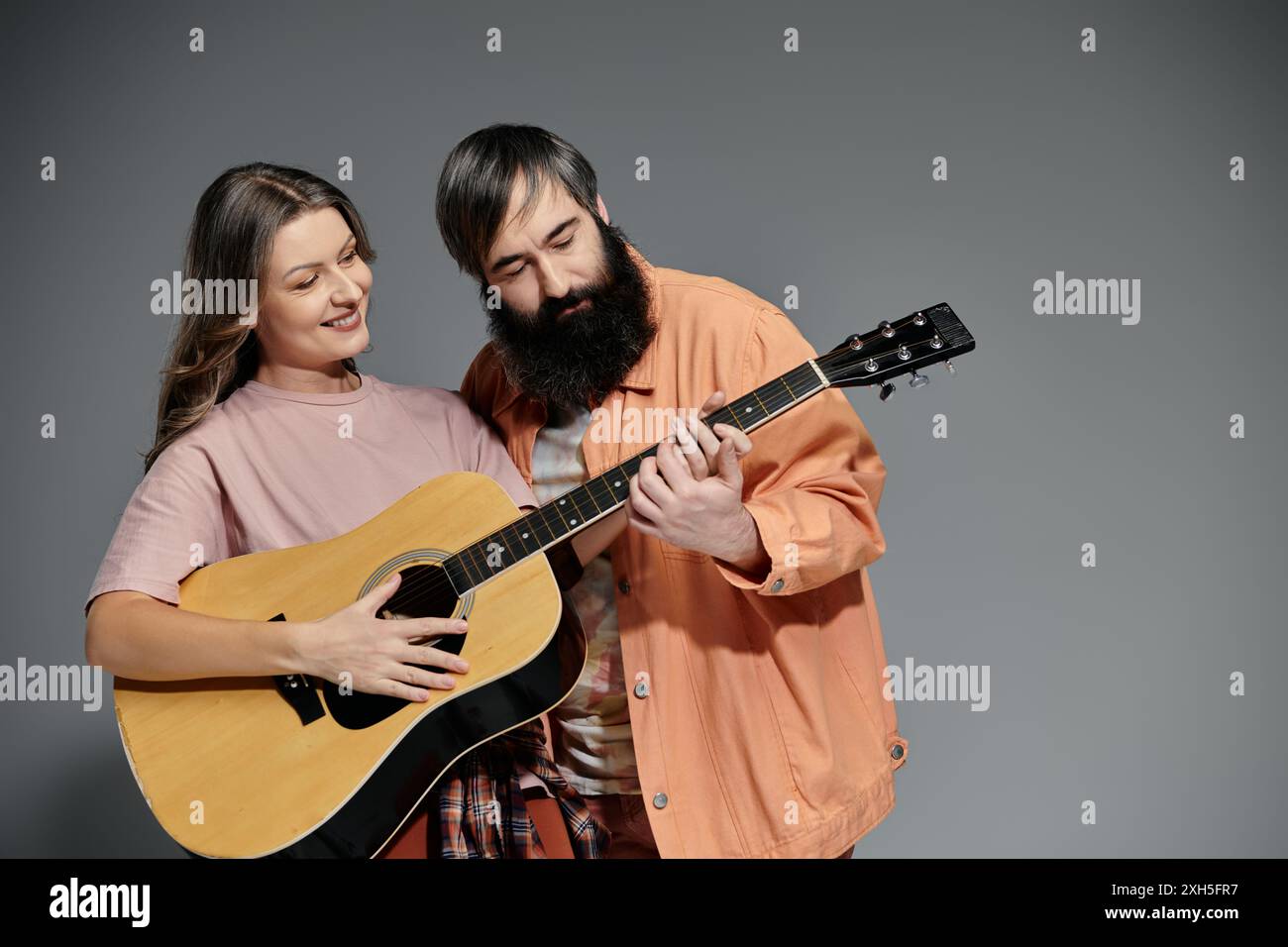 A loving couple poses together, the man playing a guitar while the ...