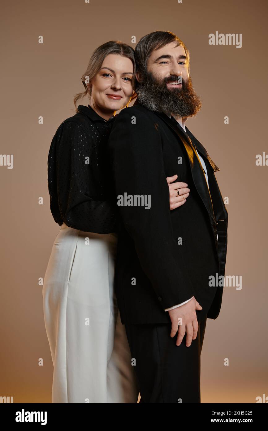 A loving couple poses together, dressed in sophisticated attire, their ...