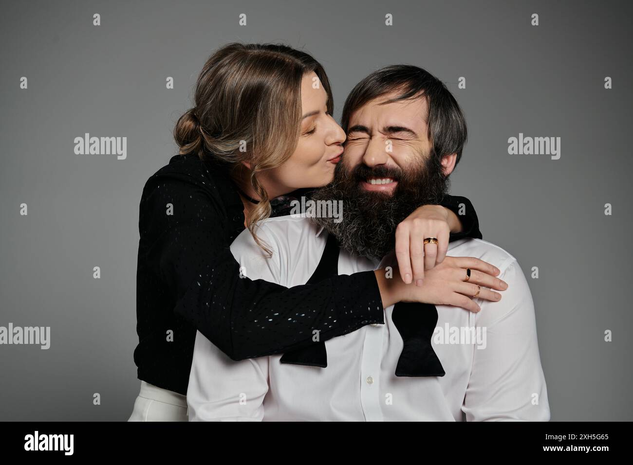 A couple dressed in formal attire embraces with affection. The woman ...