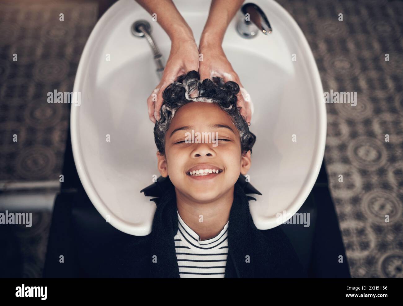 Wash, girl child and hairdresser with hair care in salon for shampoo ...