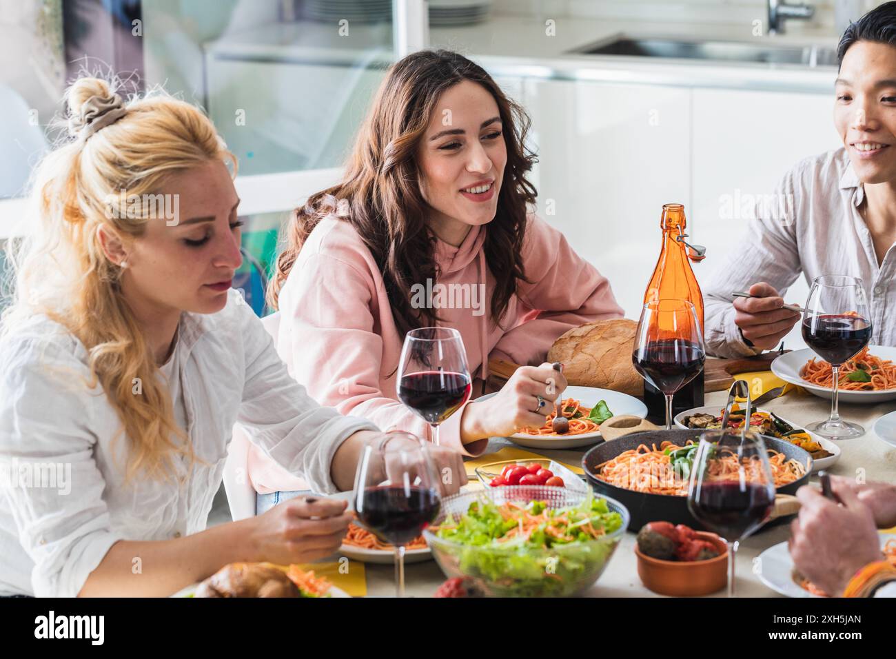 Group of friends enjoying delicious pasta and wine during lunch at home ...