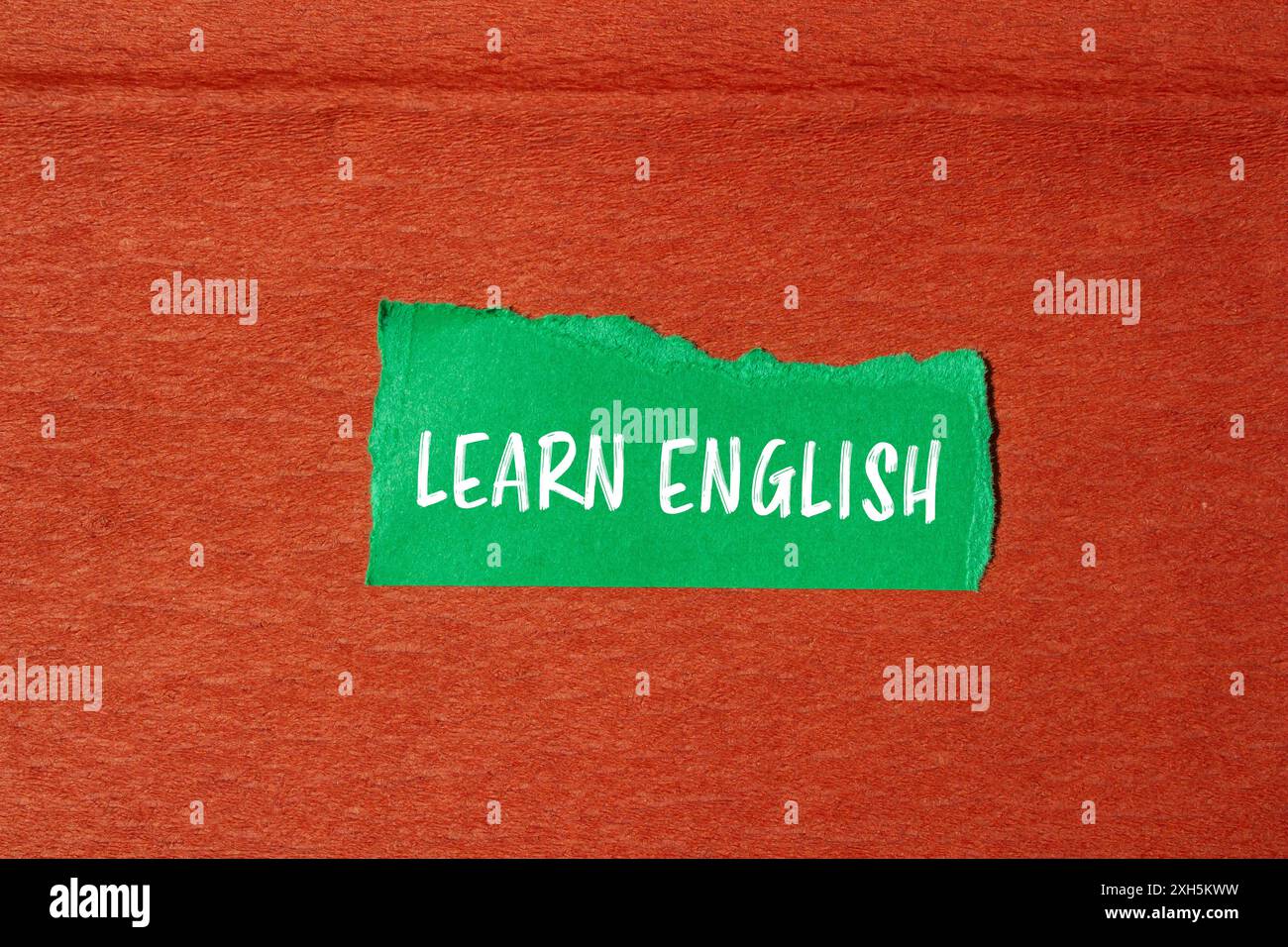 Learn english message written on ripped torn green paper piece with brown background. Conceptual ...
