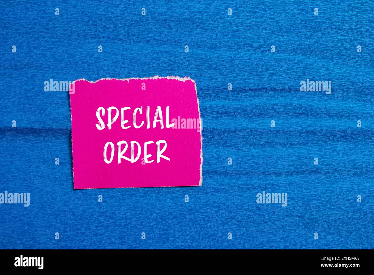 Special order message written on ripped torn pink paper piece with blue background. Conceptual ...