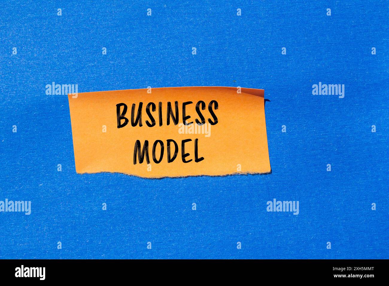 Business model message written on ripped torn orange paper piece with blue background ...