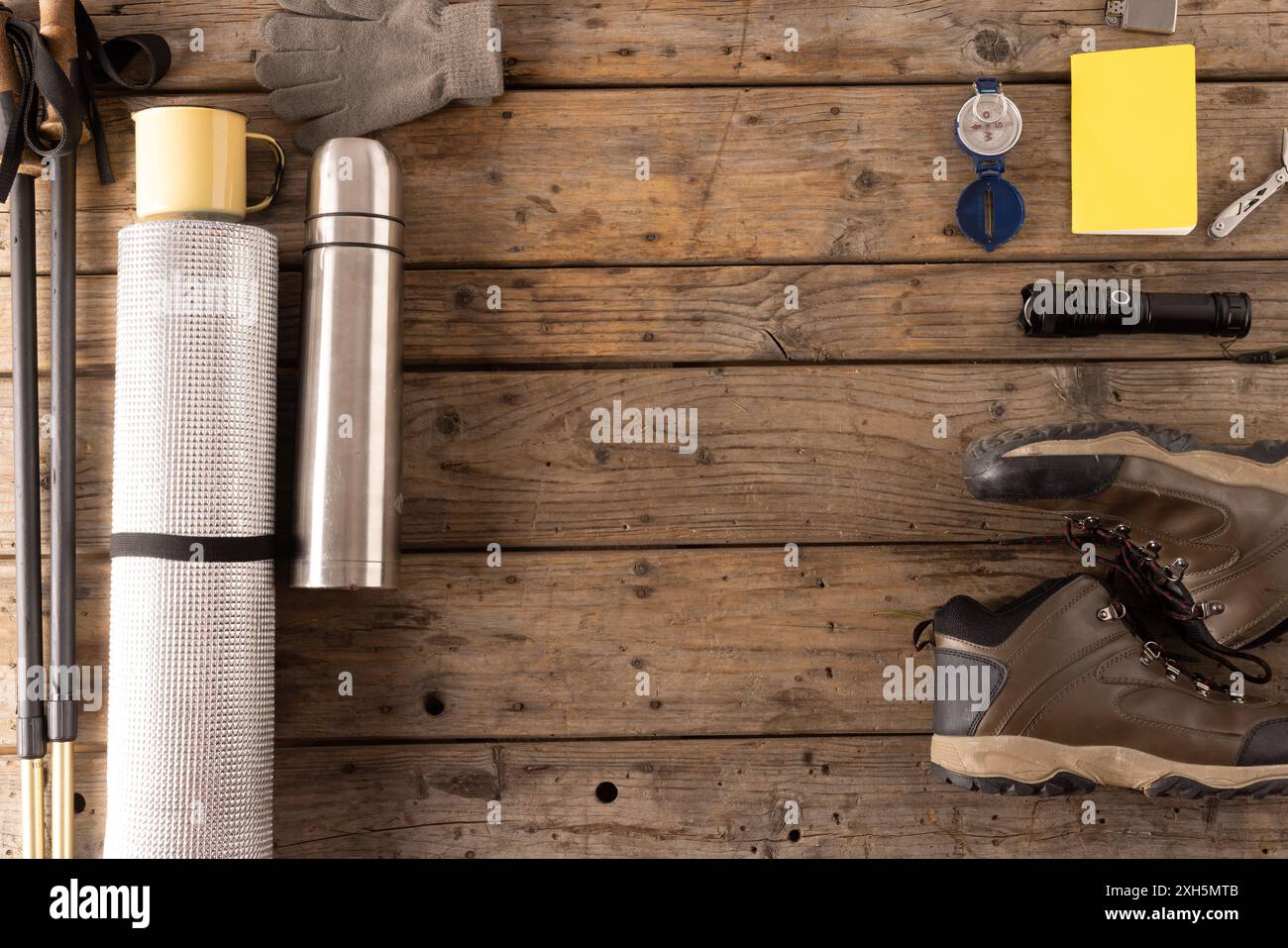 Outdoor hiking gear is neatly arranged on a wooden surface, with copy ...