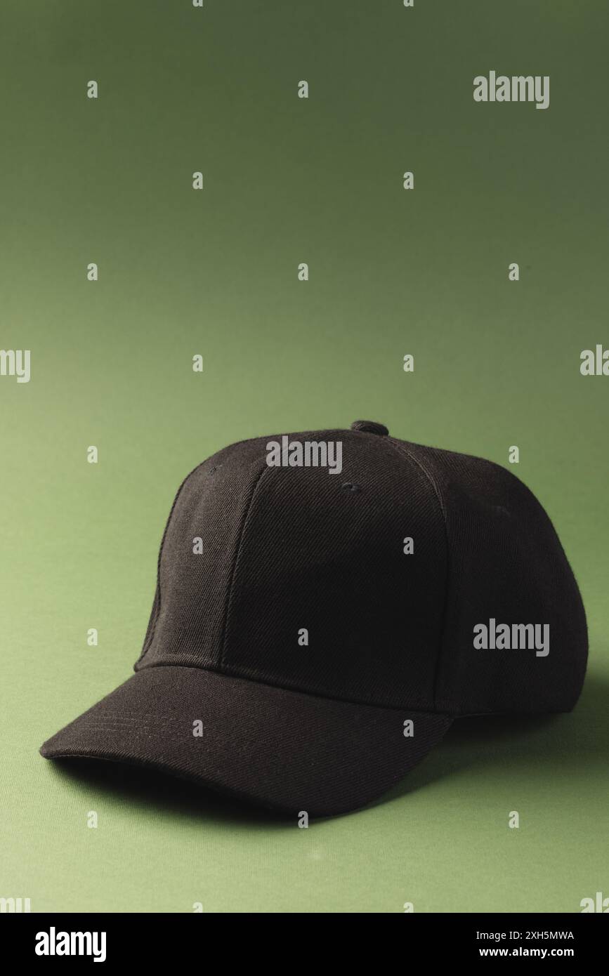 A plain black baseball cap is positioned against a green background ...