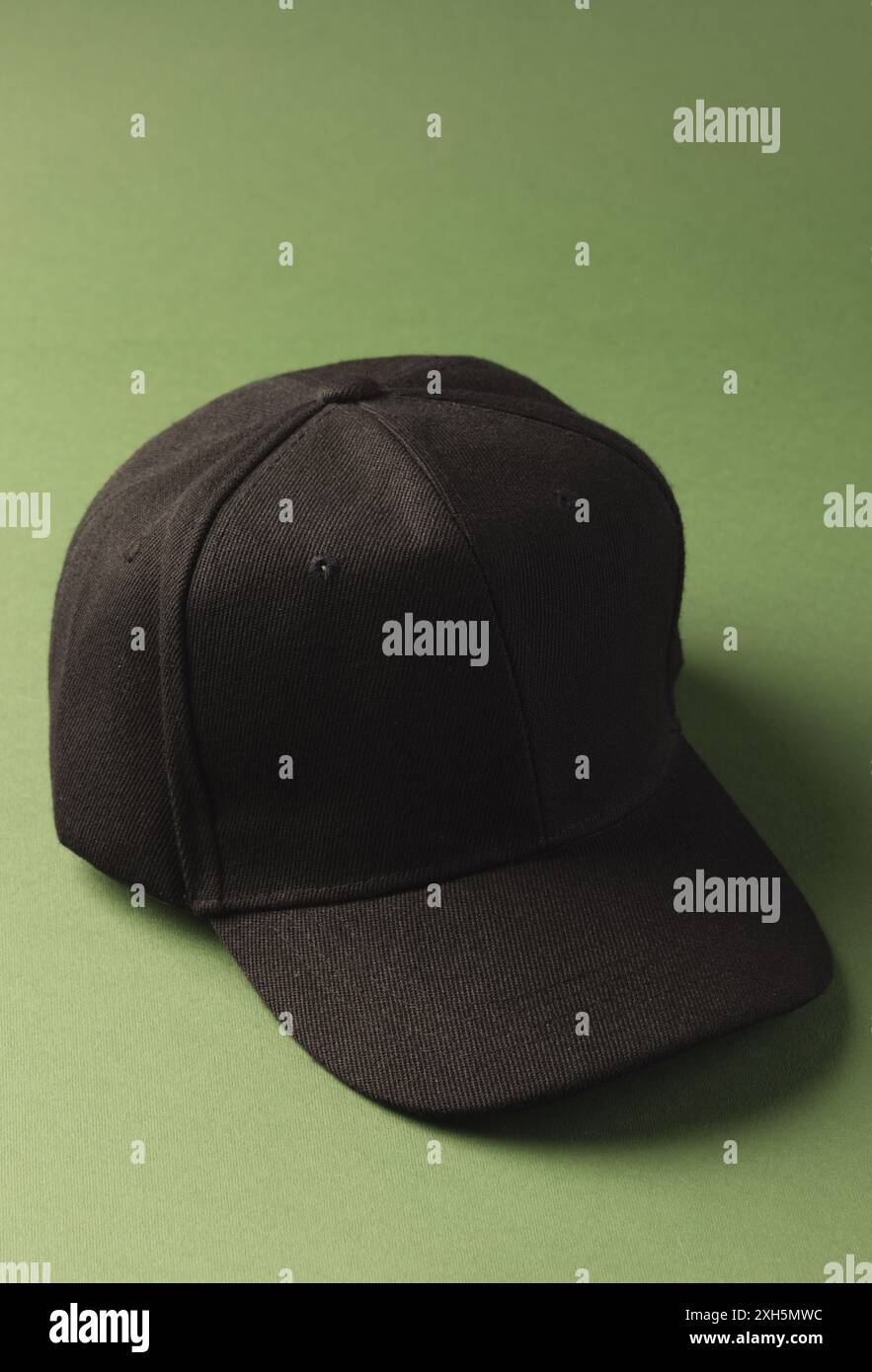 A black baseball cap is positioned against a green background, with ...