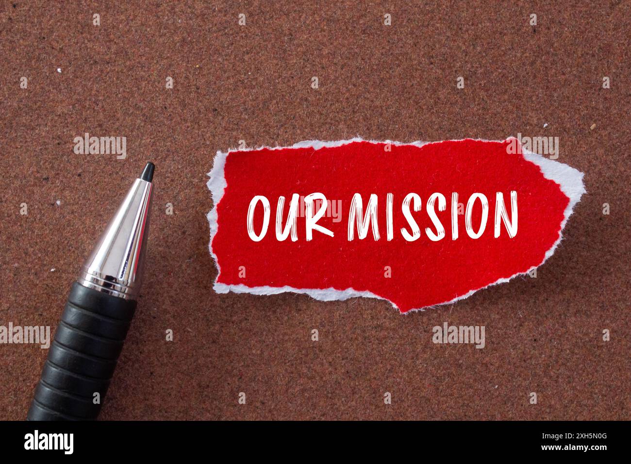 Our mission message written on ripped torn red paper and a pen with ...