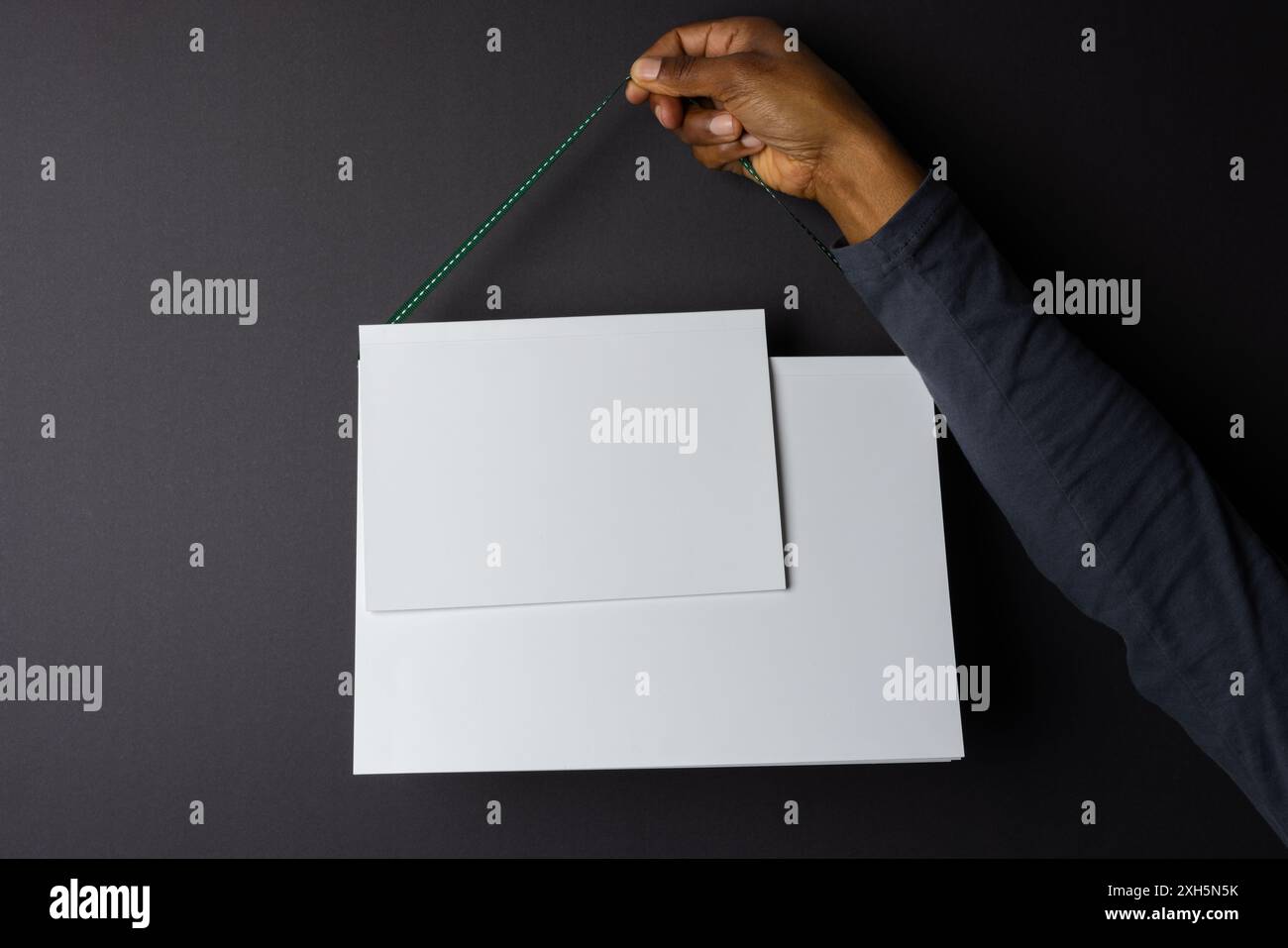 African American man measuring an envelope on a dark surface with copy ...