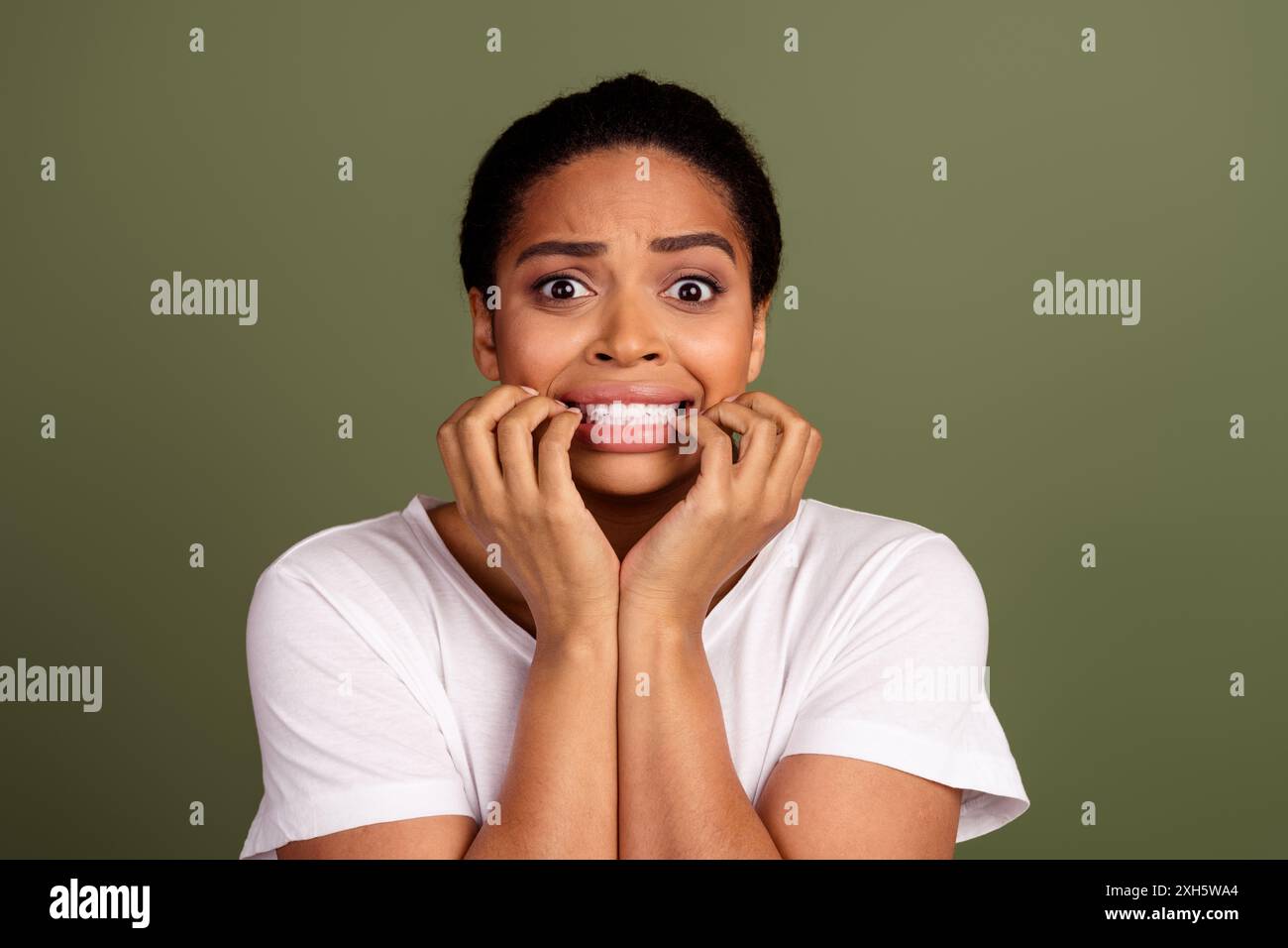 Portrait of pretty young woman bite finger nails wear white t-shirt ...