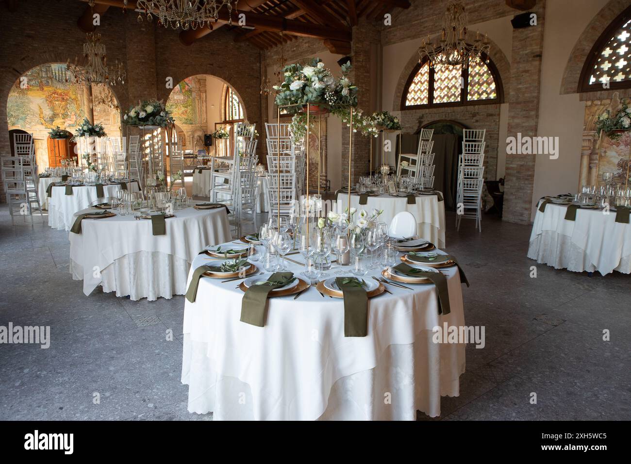 Round tables with white tablecloths decorated with flower arrangements ...