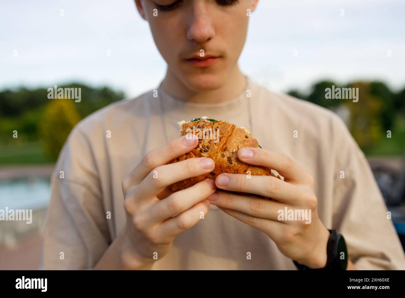 Selective focus on hands of young person eating sandwich outdoors Stock ...