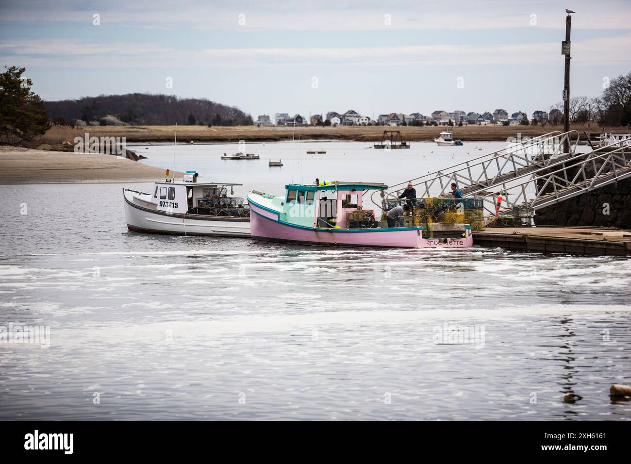 Pink Fishing boats docked with workers handling crab traps Stock Photo ...