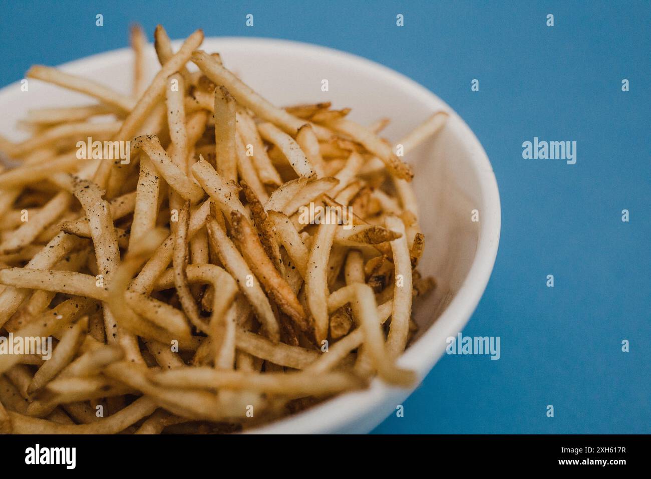 Bowl of seasoned french fries on a blue background Stock Photo - Alamy
