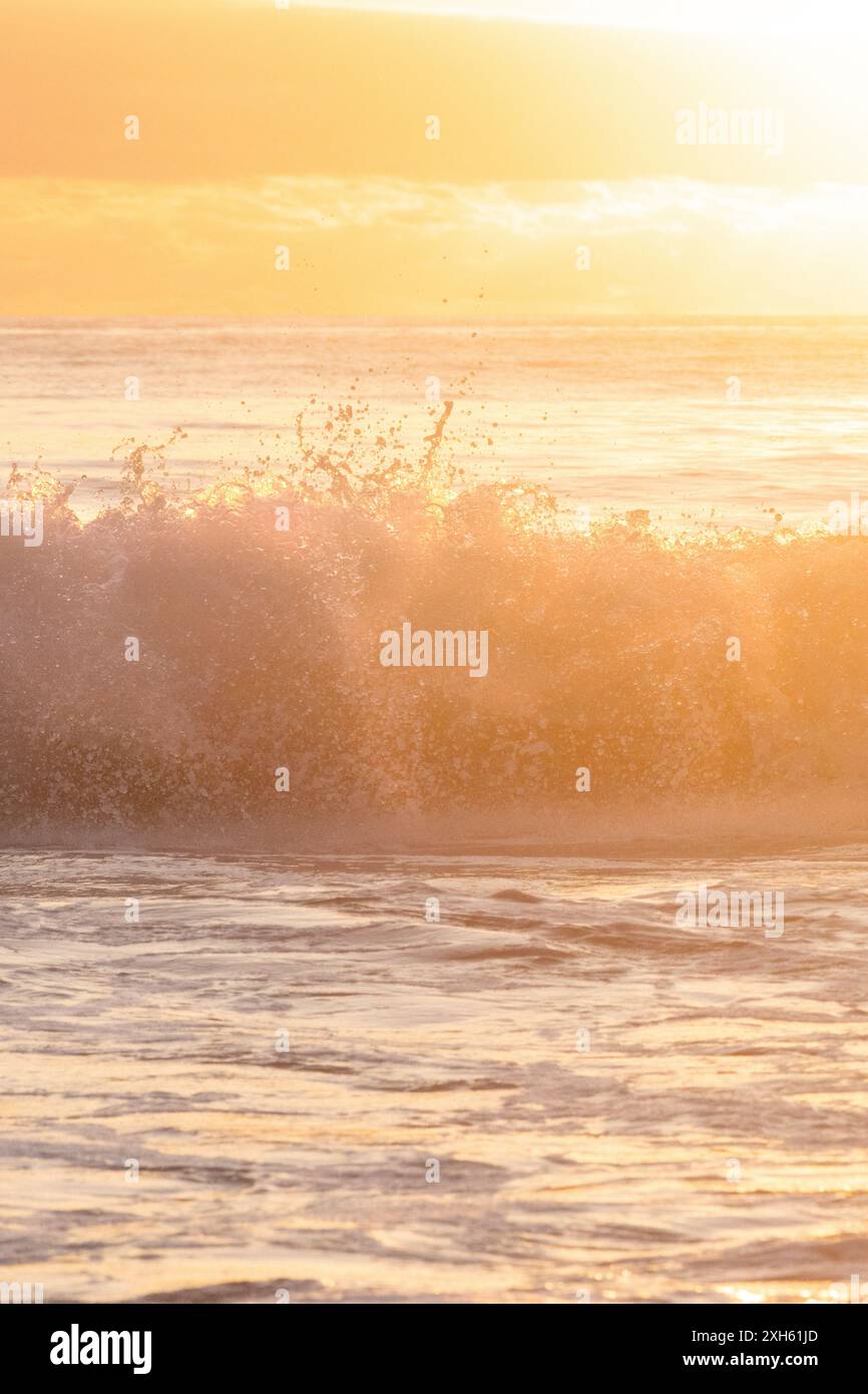 Sun illuminating a wave with golden light at sunrise Stock Photo - Alamy