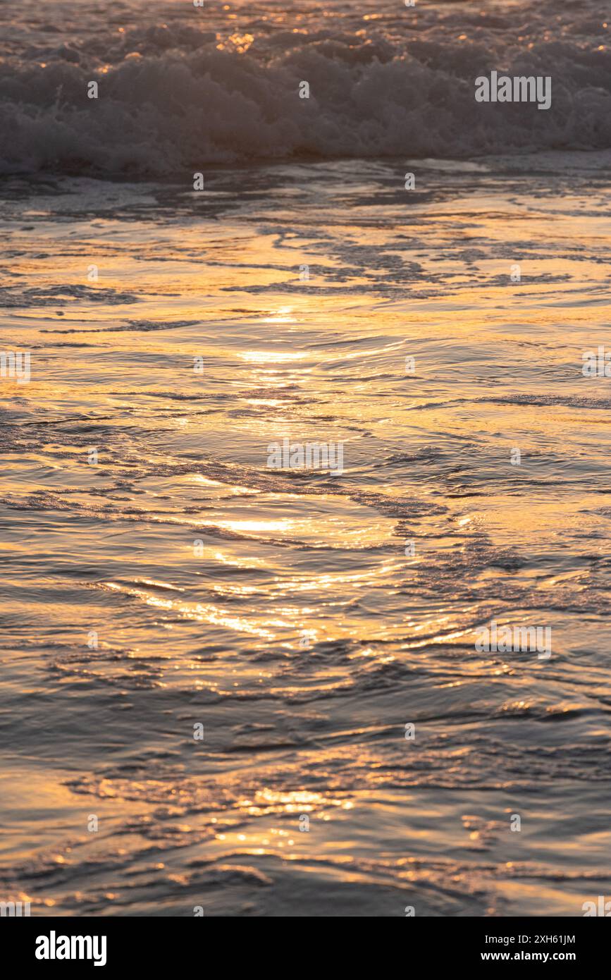 Golden sunset reflecting on shiny metallic ocean waves Stock Photo - Alamy