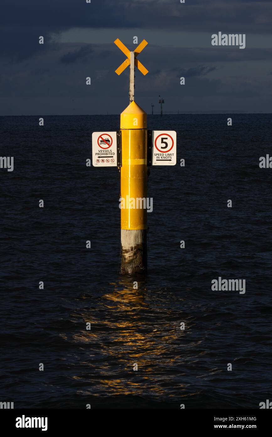 Yellow marine navigation marker with speed limit sign in calm water ...