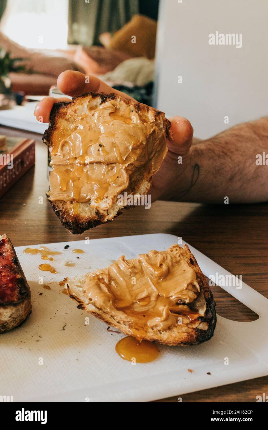 Man holds homemade sourdough toast with peanut butter and honey Stock ...