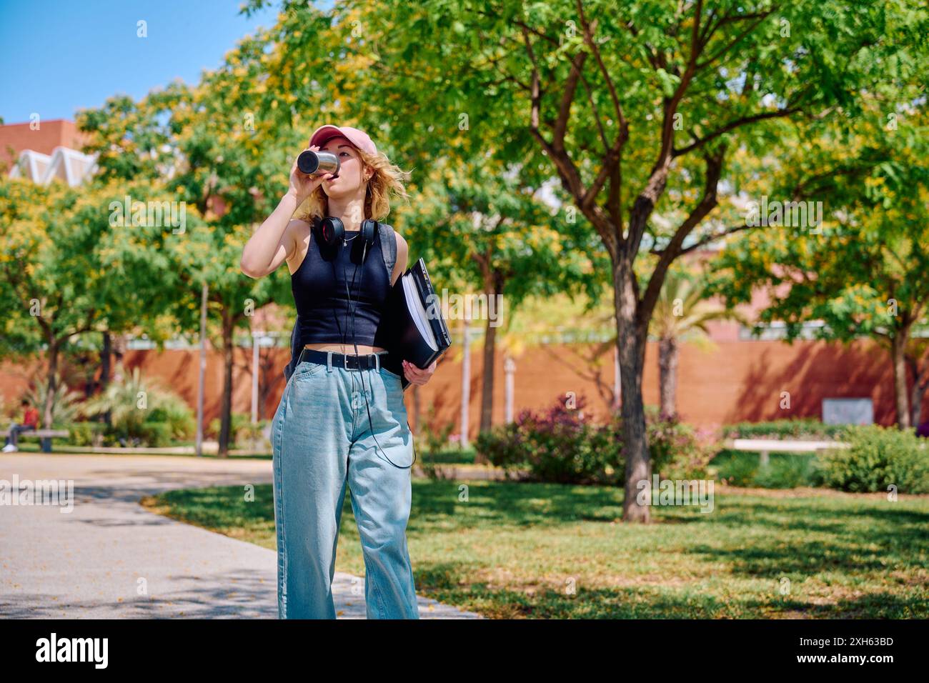 Student drinking coffee on campus walkway Stock Photo - Alamy