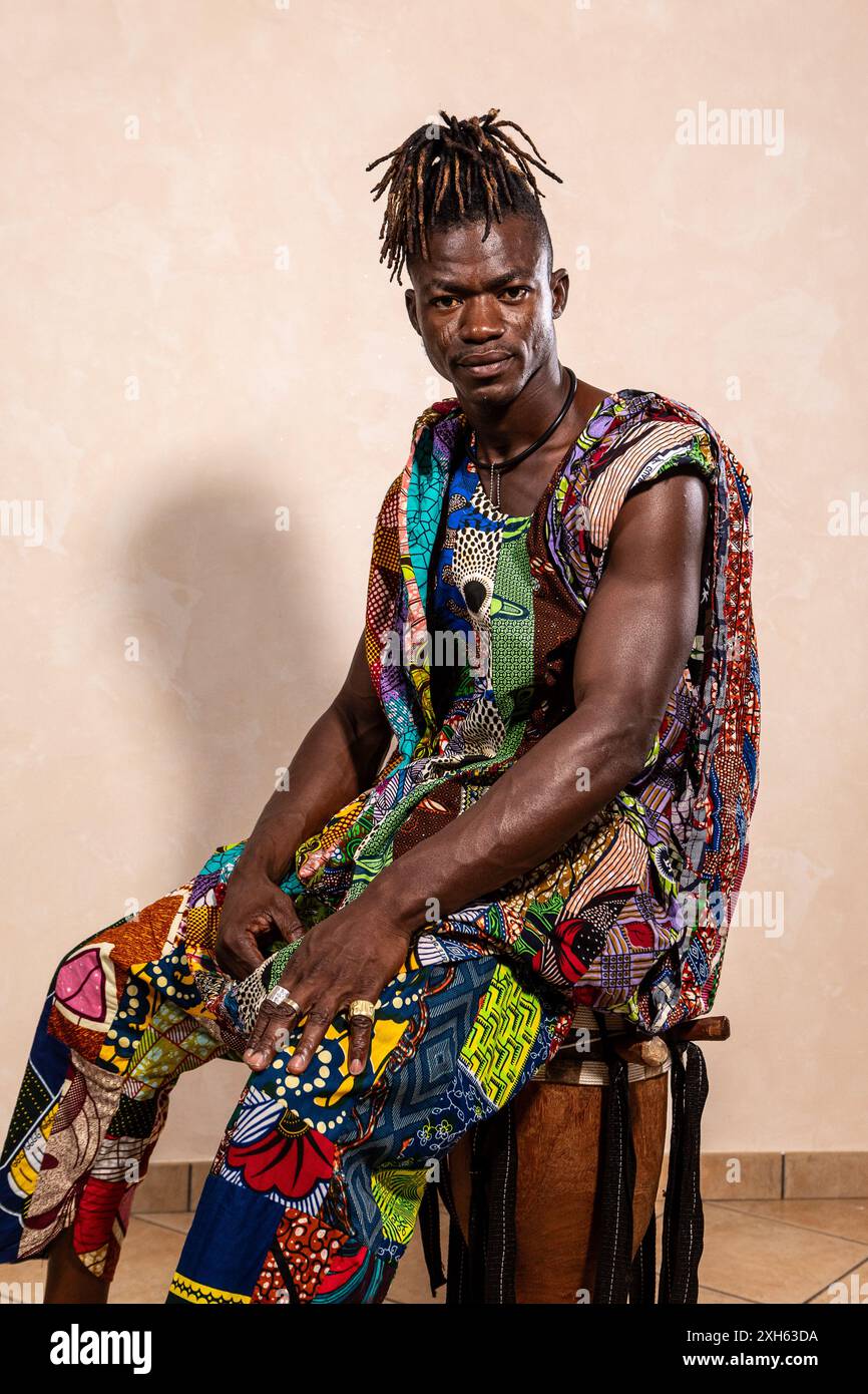 Musician wearing traditional african clothes sitting on djembe drum ...