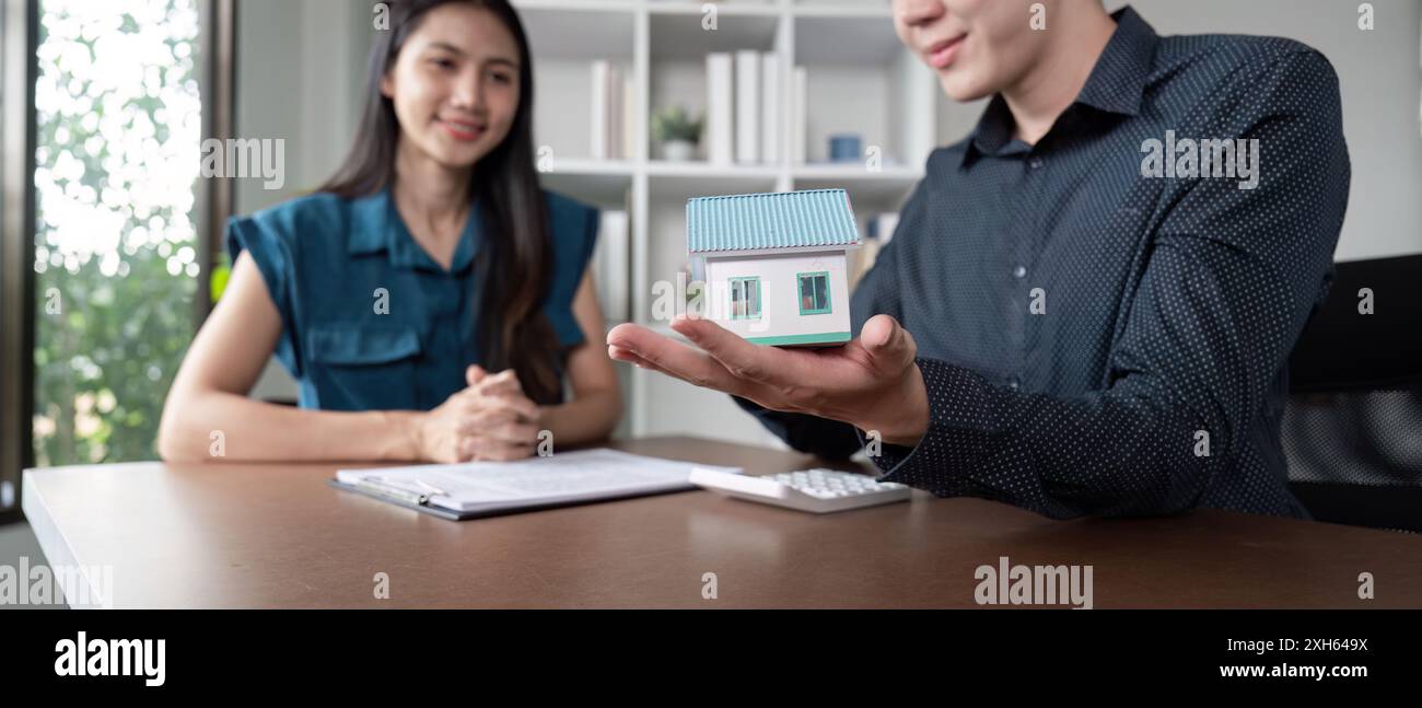 Real Estate Agent Presenting House Model to Client in Office Setting ...