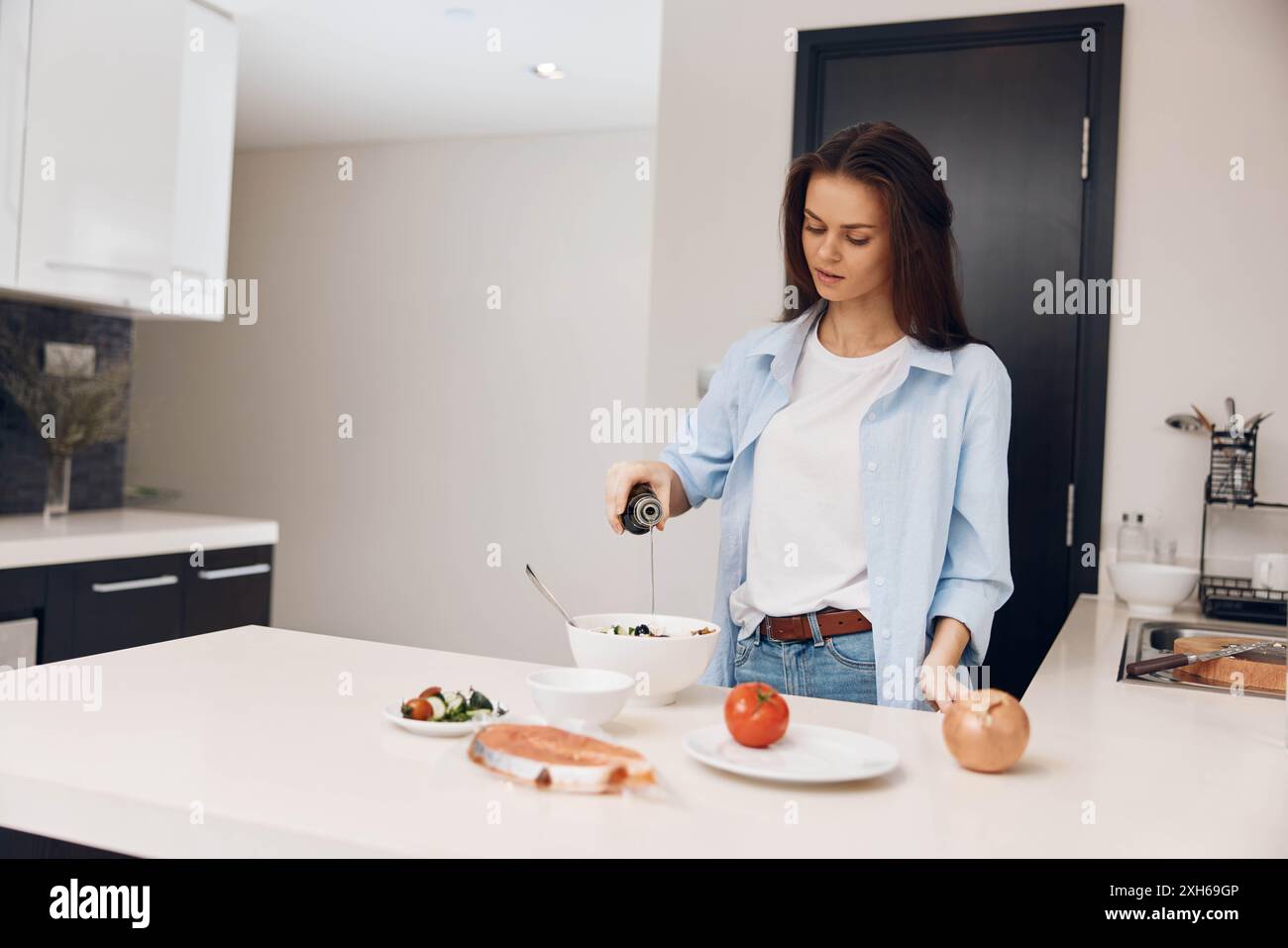 Attractive young woman cooking healthy food in her home kitchen ...
