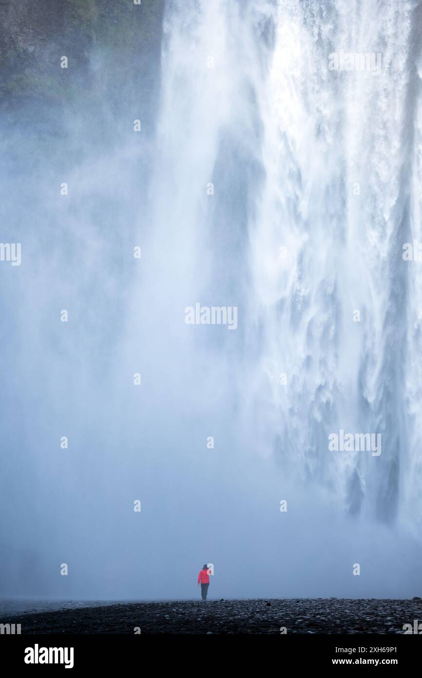 Stunning view of the Skógafoss Waterfall with a tourist wearing a red ...