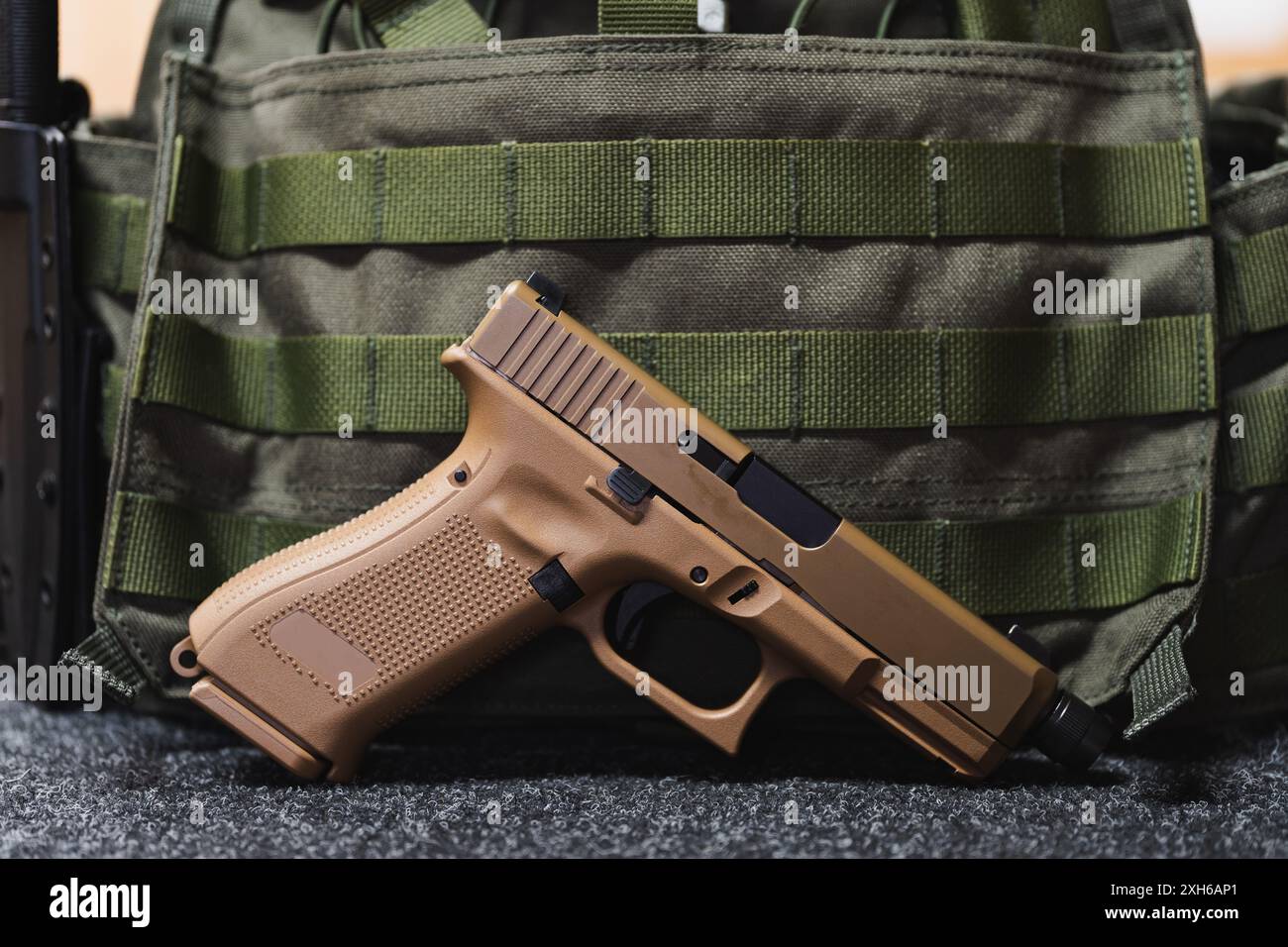 Military camouflage 9mm caliber pistol near the plate carrier body ...