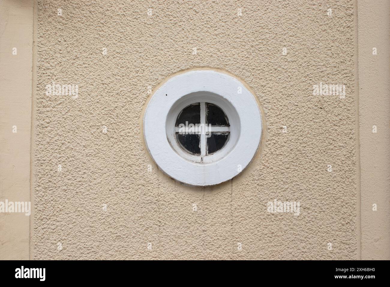 round framed window with wooden grille in the middle and building wall ...